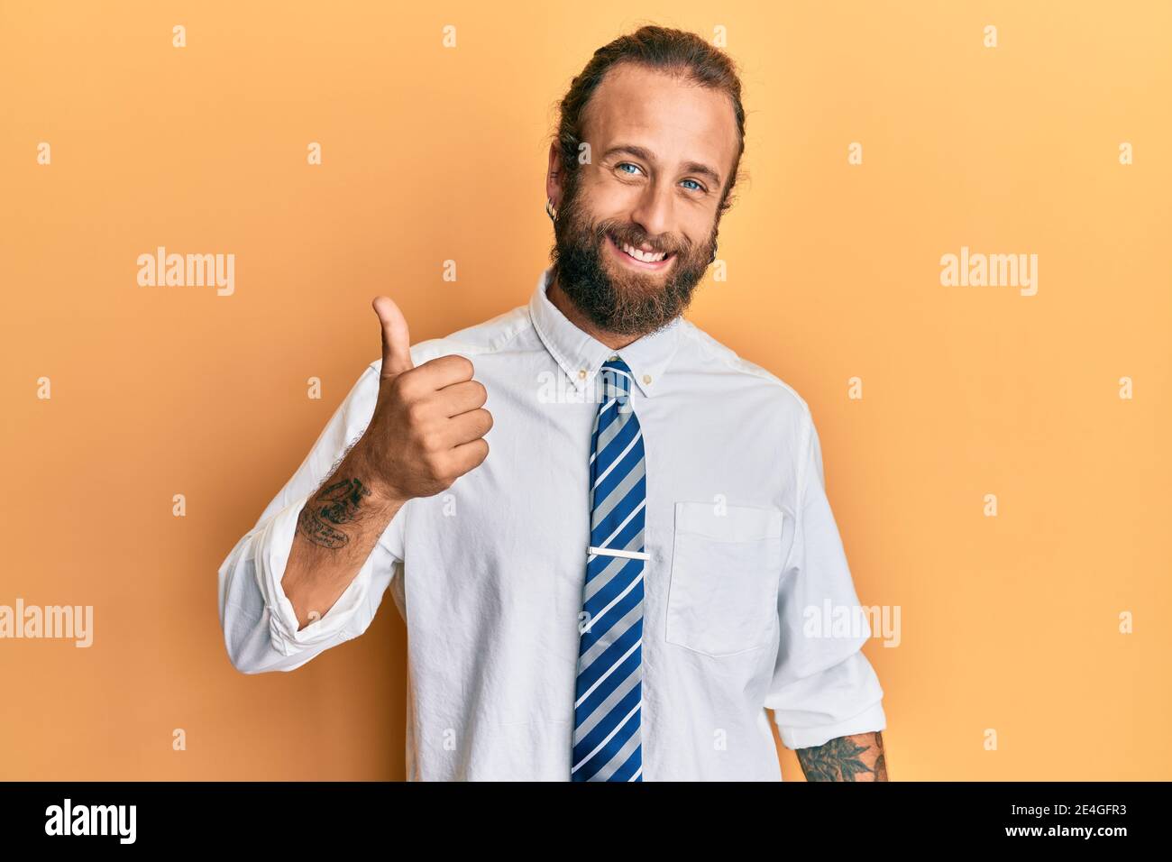 Handsome man with beard and long hair wearing business clothes doing ...