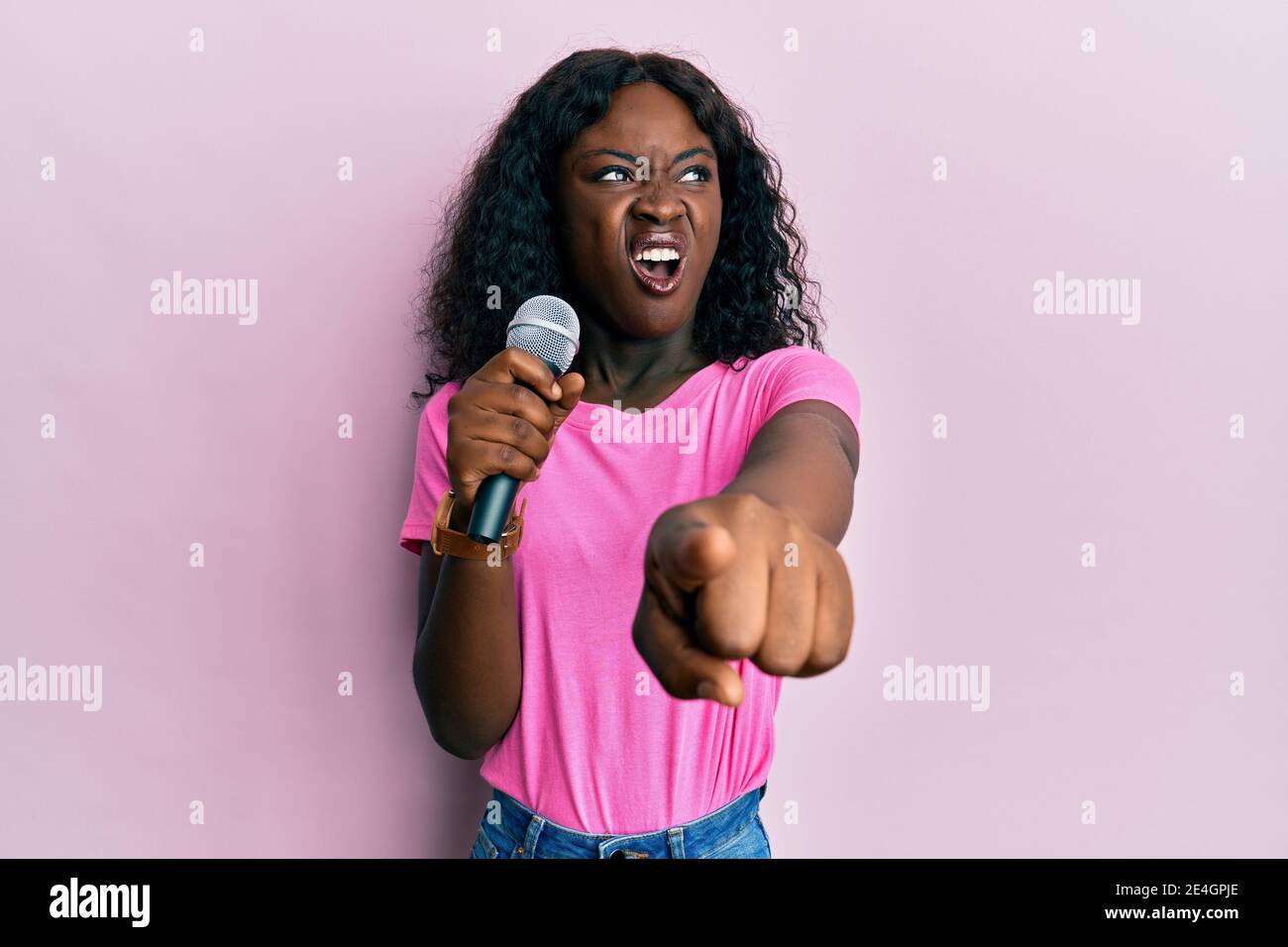 Beautiful african young woman singing song using microphone pointing to ...