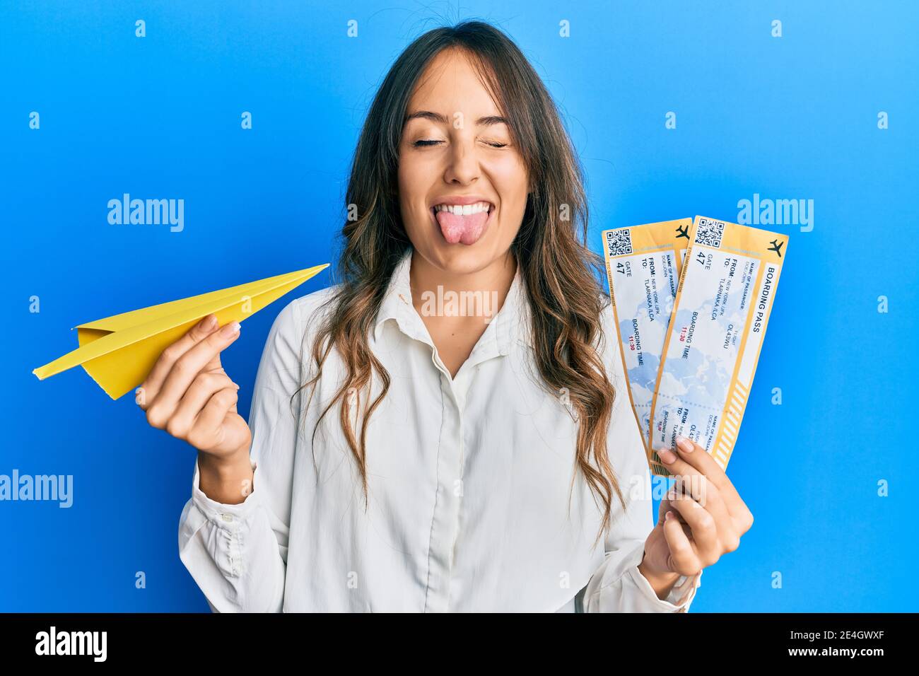 Young brunette woman holding paper airplane and boarding pass sticking ...
