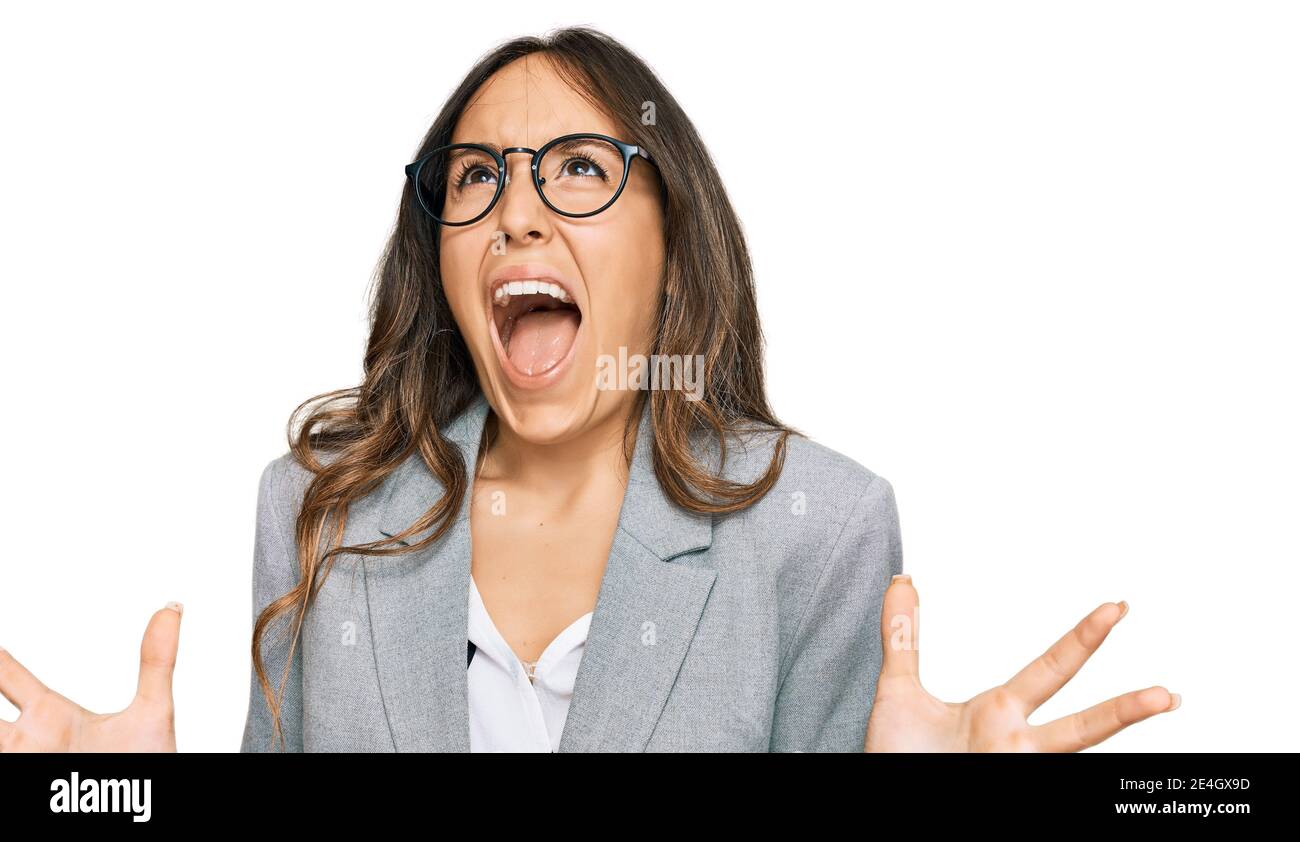 Young brunette woman wearing business clothes crazy and mad shouting ...