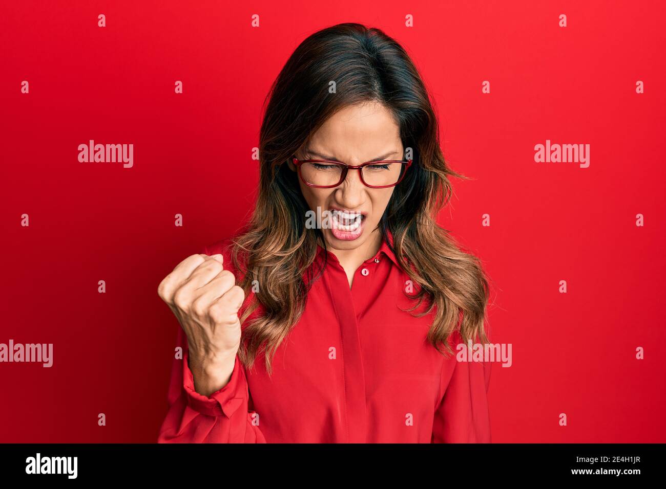 Young latin woman wearing casual clothes and glasses angry and mad ...