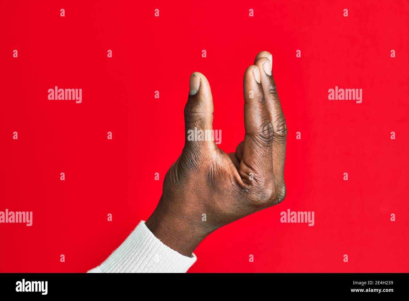 Arm and hand of african american black young man over red isolated ...