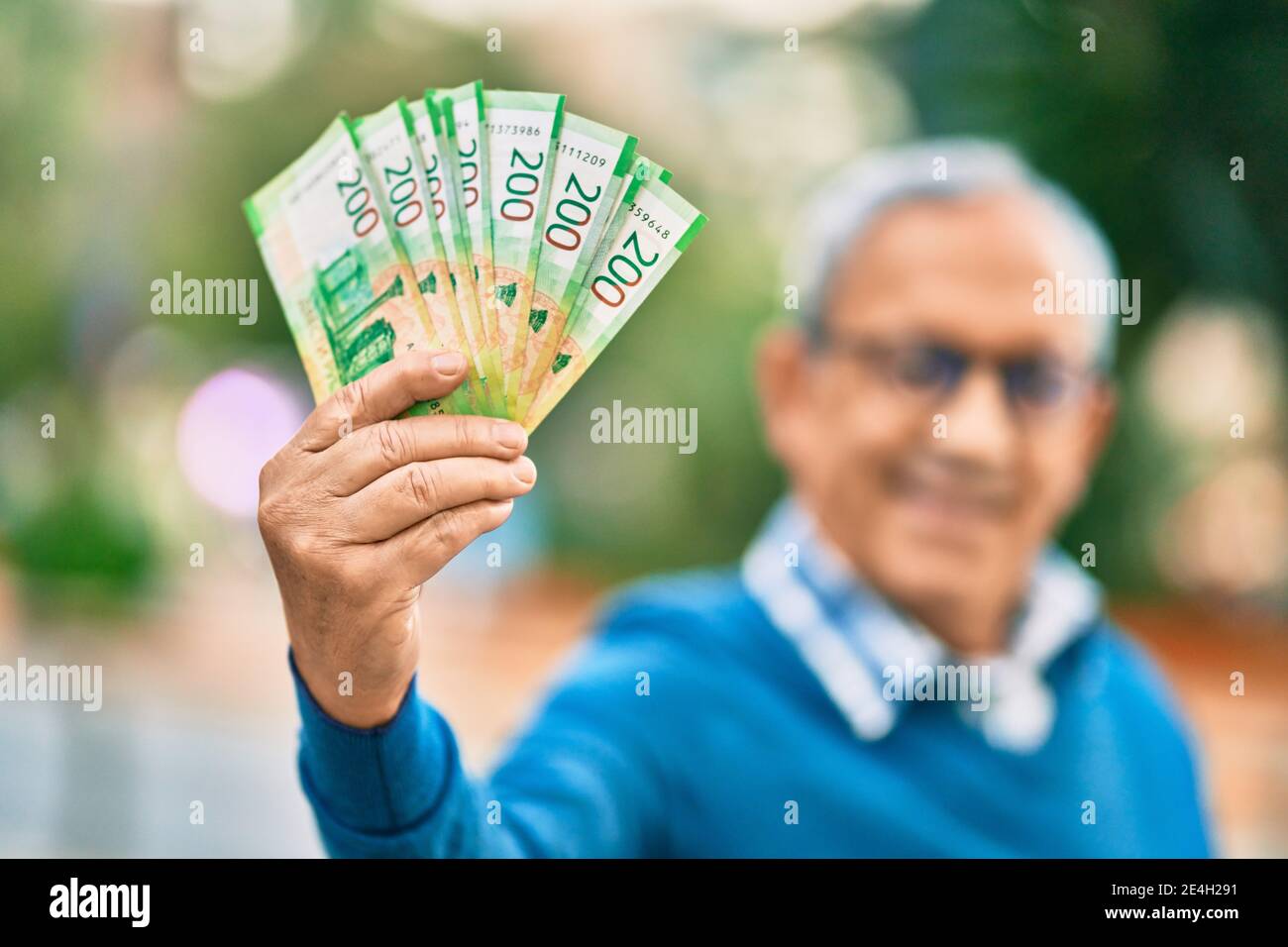 Senior grey-haired man smiling happy holding russian ruble banknotes at ...