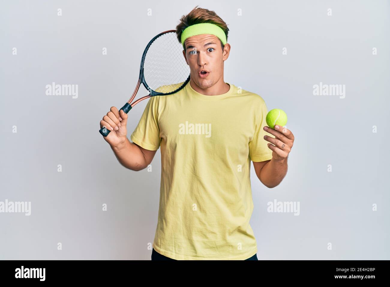 Handsome caucasian man playing tennis holding racket and ball scared ...