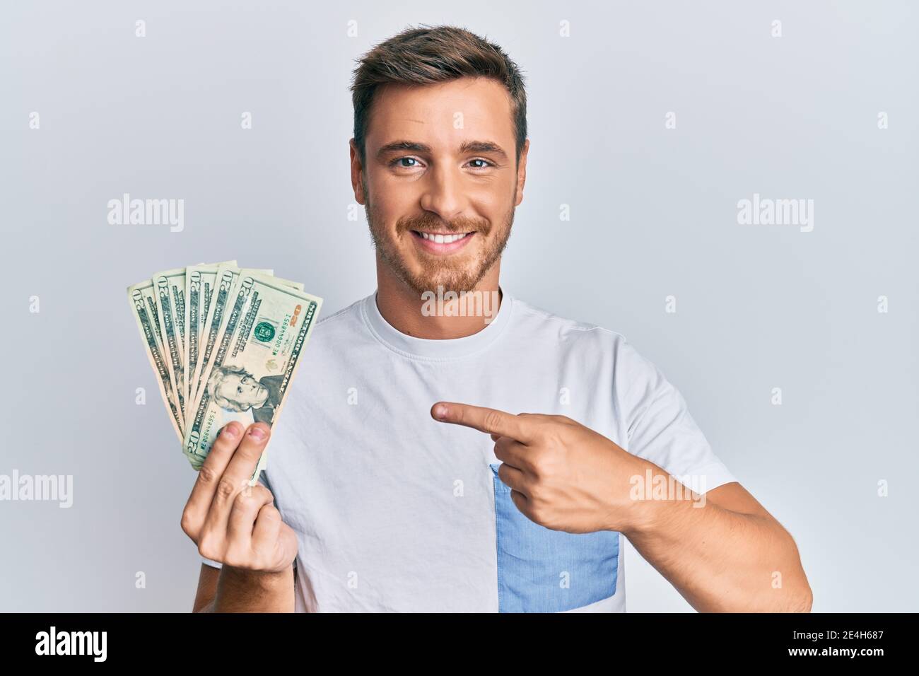 Handsome caucasian man holding 20 dollars banknote smiling happy ...