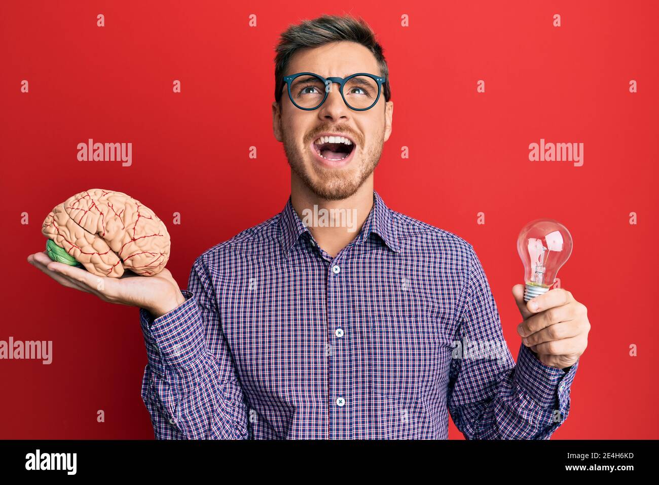 Handsome caucasian man holding brain and lightbulb for inspiration and ...