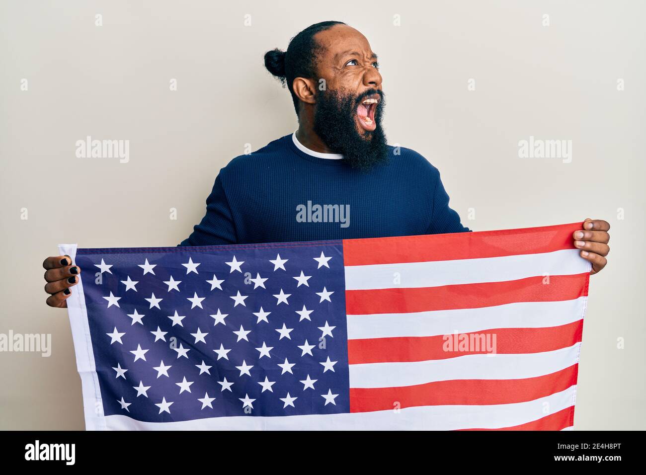 Young african american man holding united states flag angry and mad ...