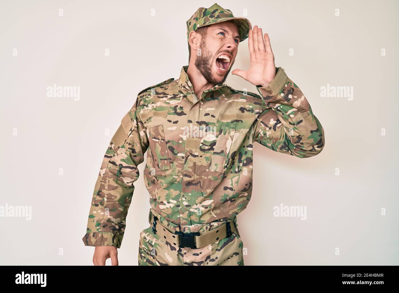 Young caucasian man wearing camouflage army uniform shouting and ...