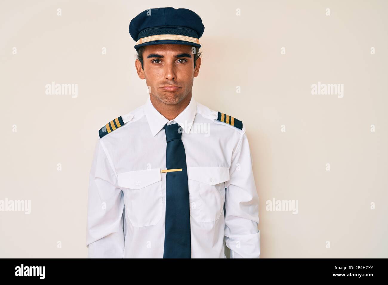 Young hispanic man wearing airplane pilot uniform depressed and worry ...