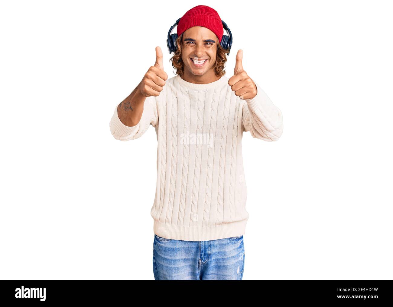 Young hispanic man listening to music using headphones approving doing ...