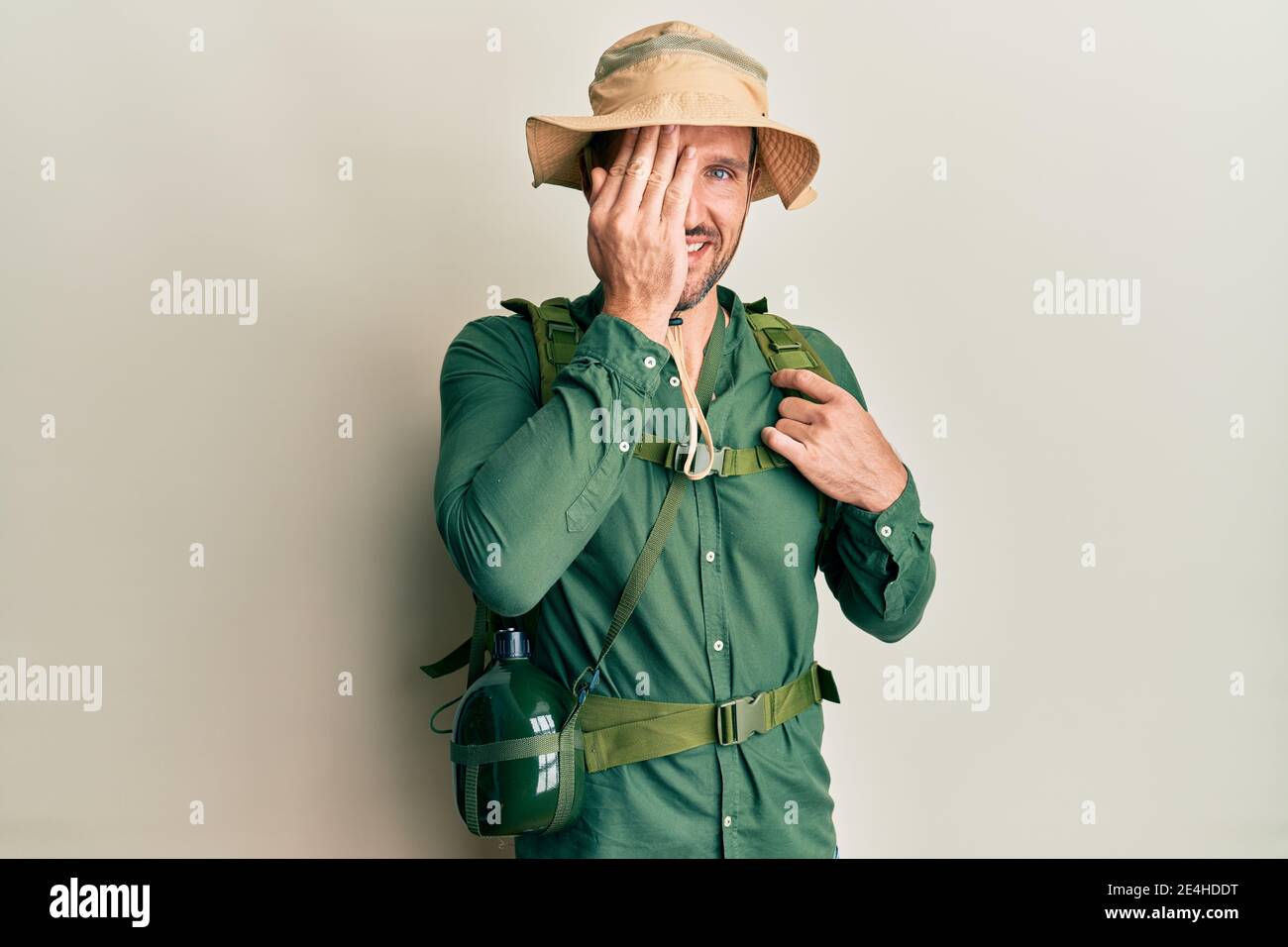 Handsome man with beard wearing explorer hat and backpack covering one ...