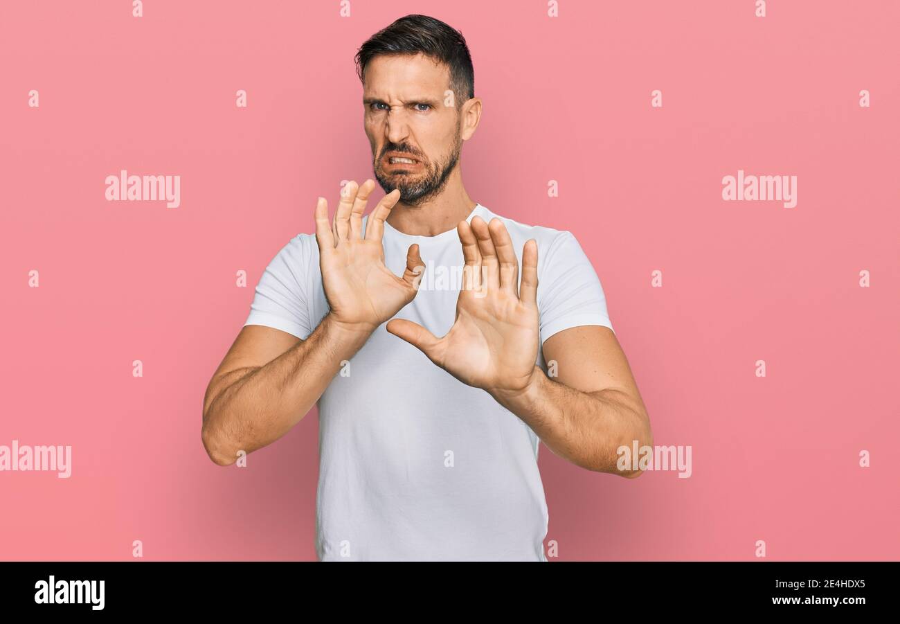 Handsome man with beard wearing casual white t shirt disgusted ...