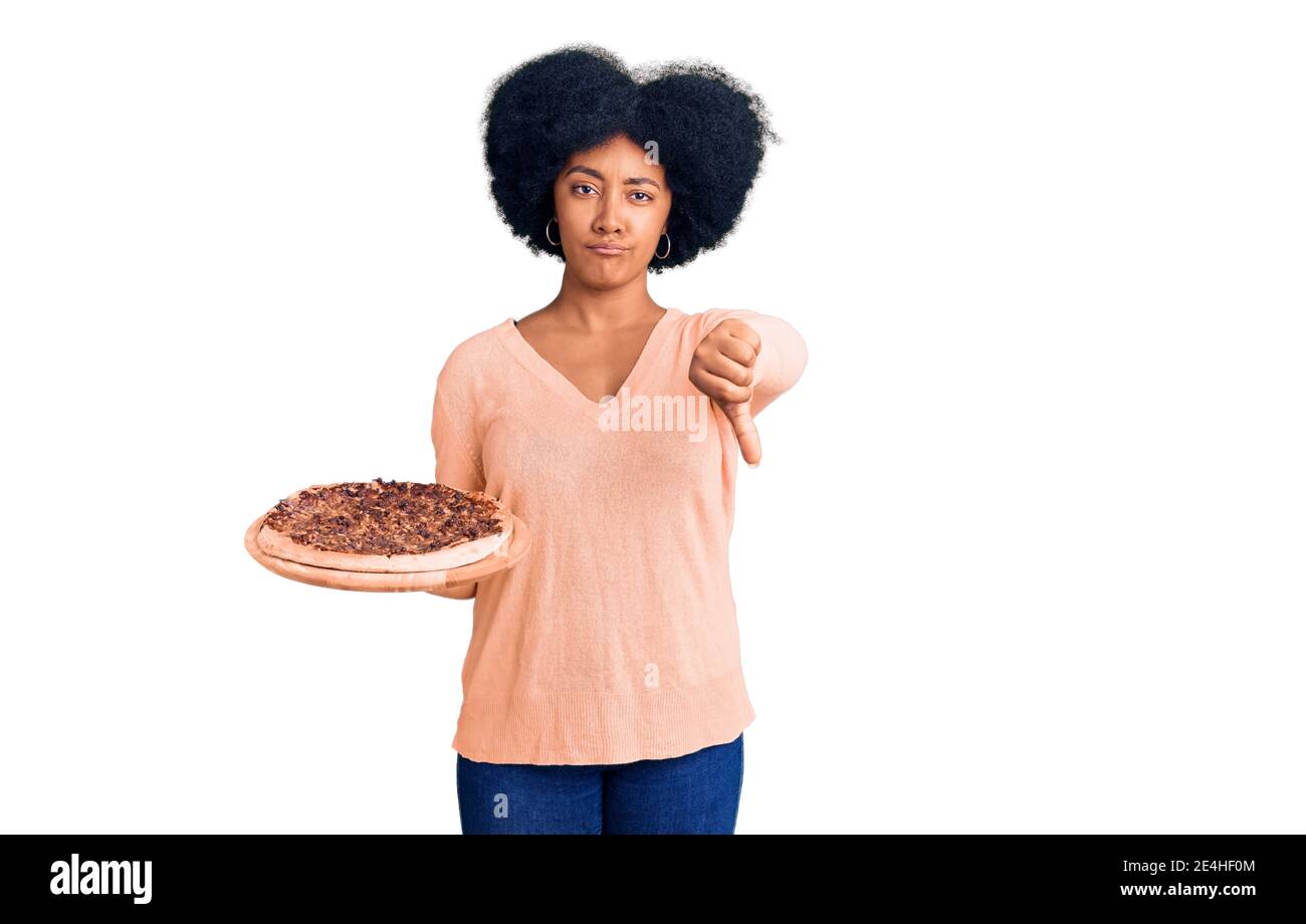 Young african american girl holding italian pizza with angry face ...
