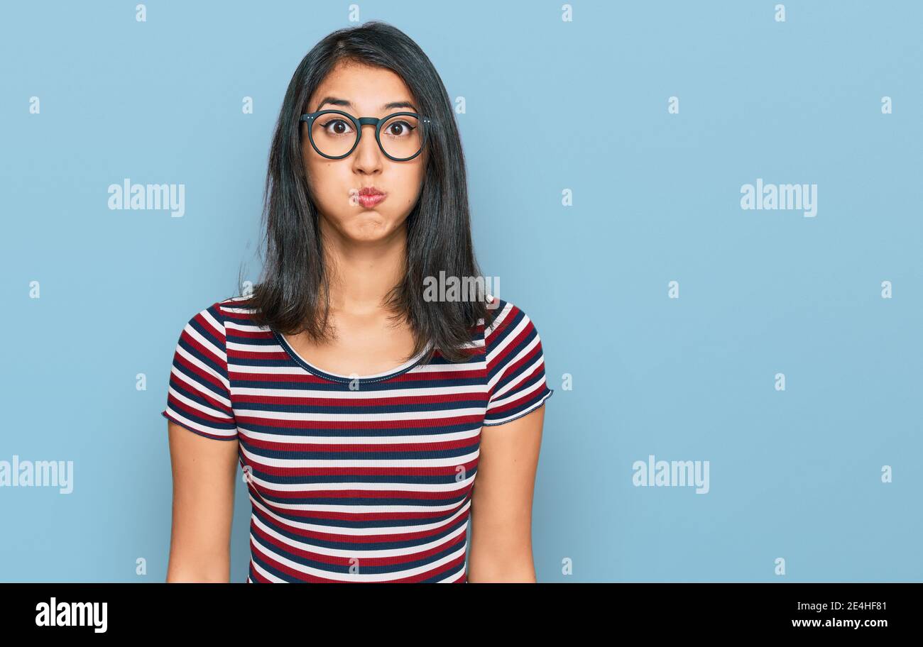 Beautiful asian young woman wearing casual clothes and glasses puffing ...