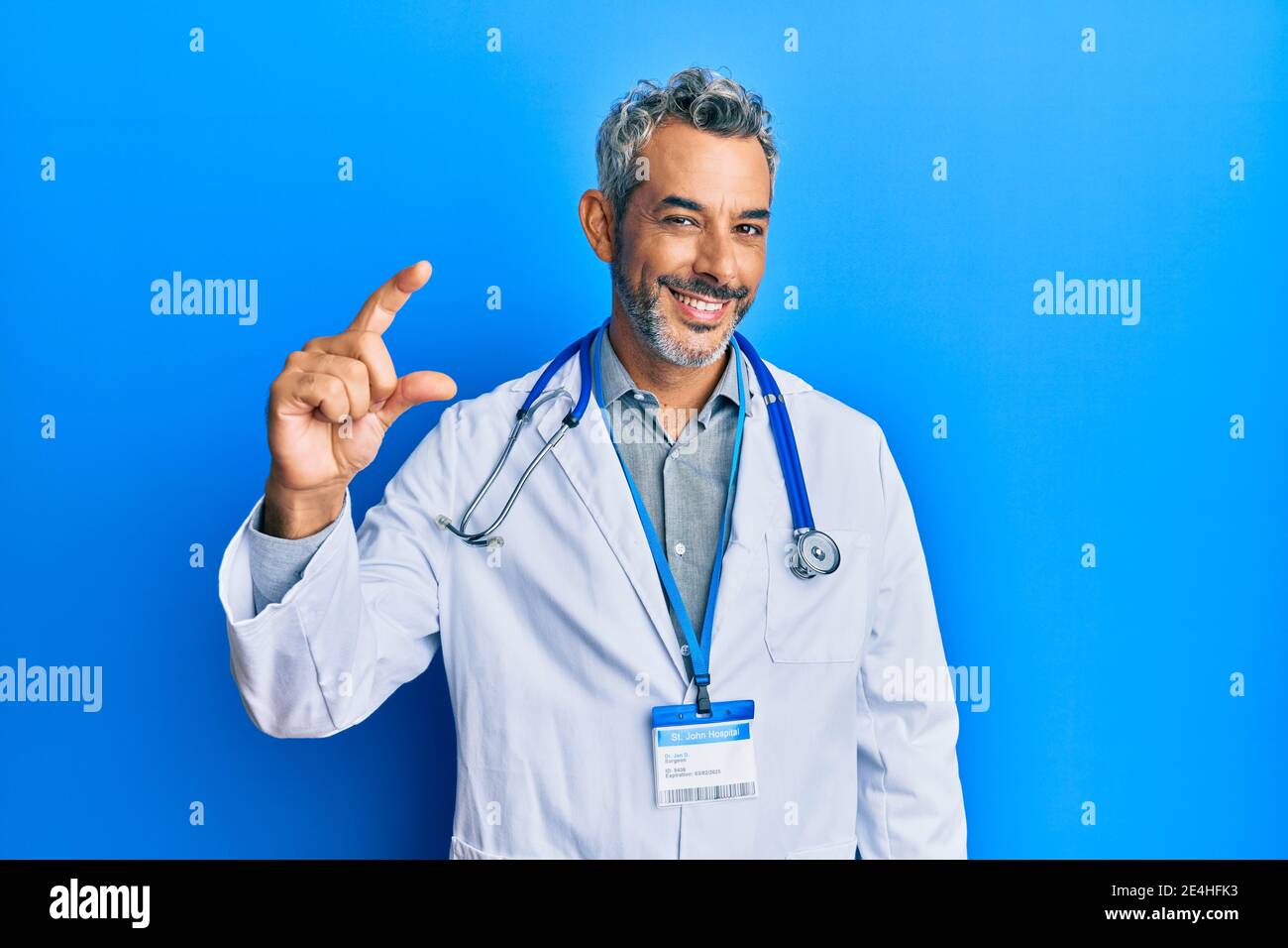 Middle age grey-haired man wearing doctor uniform and stethoscope ...