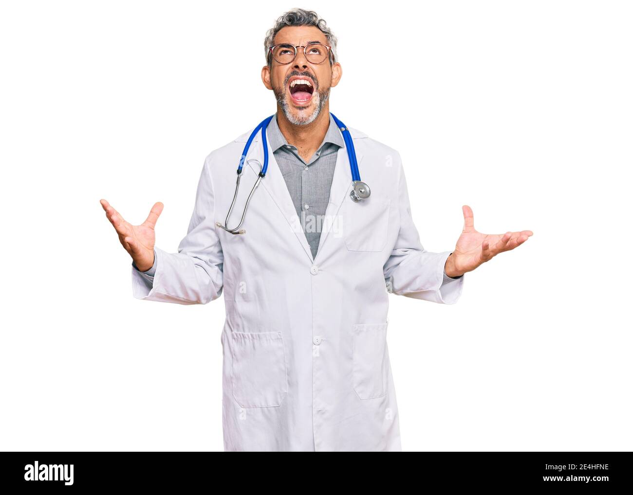 Middle age grey-haired man wearing doctor uniform and stethoscope crazy ...