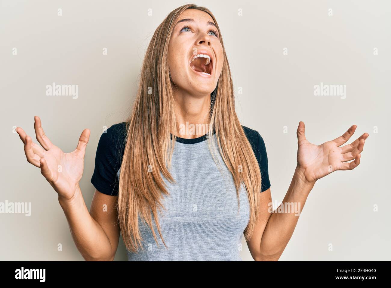 Young blonde woman wearing casual clothes crazy and mad shouting and ...