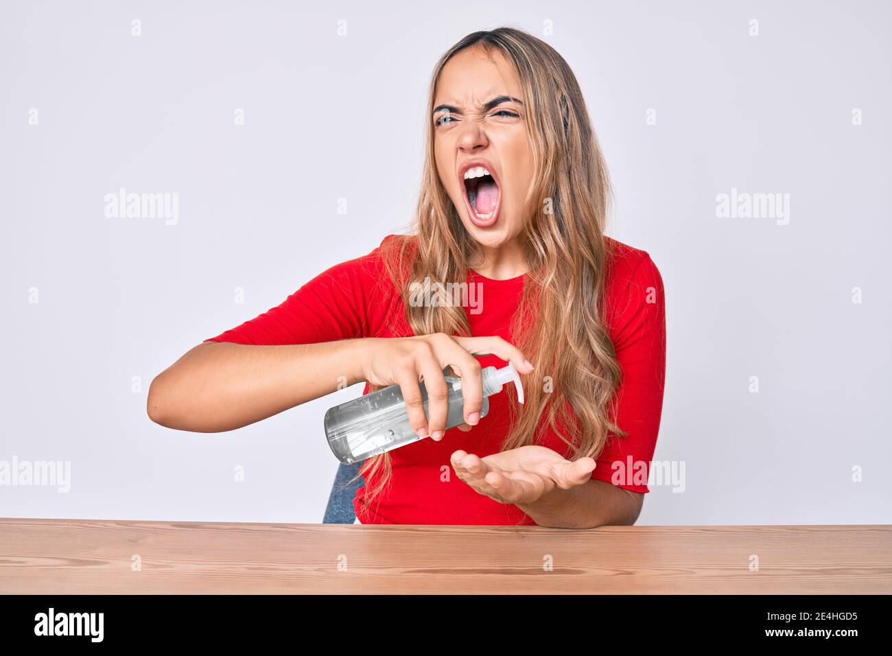 Young beautiful blonde woman sitting on the table cleaning hands using ...