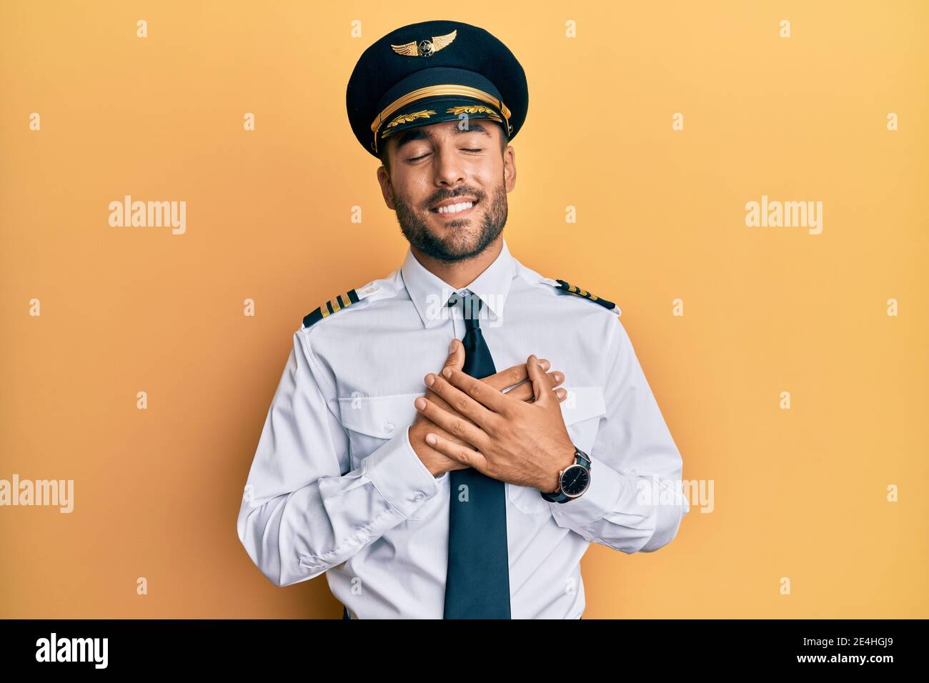 Handsome hispanic man wearing airplane pilot uniform smiling with hands ...