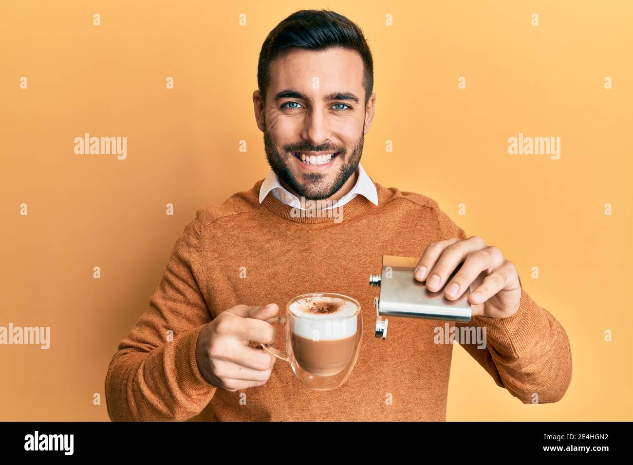 Young hispanic man drinking a cup of coffee with alcohol smiling with a ...