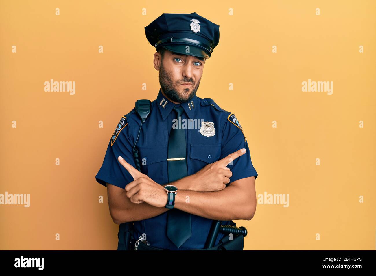 Handsome hispanic man wearing police uniform pointing to both sides ...
