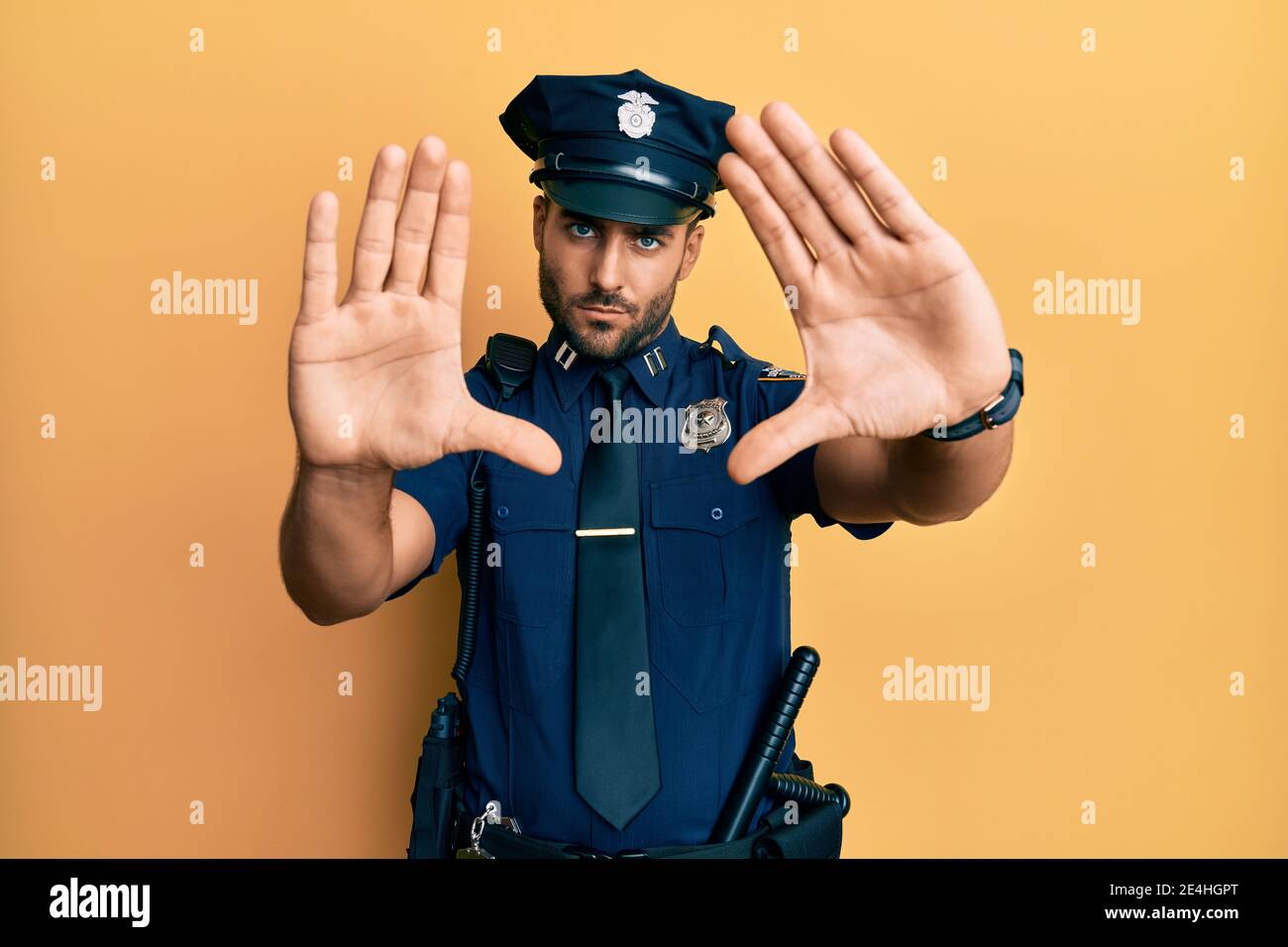 Handsome hispanic man wearing police uniform doing frame using hands ...