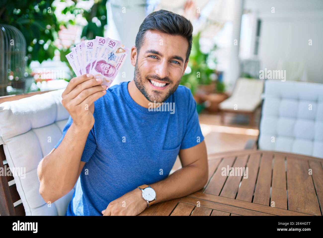 Young hispanic man smiling happy holding mexican pesos banknotes at the ...