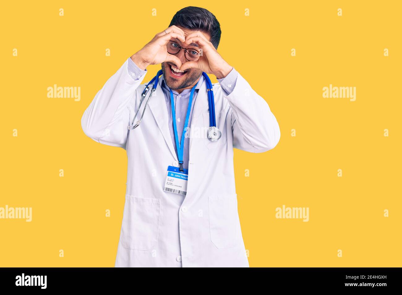 Young hispanic man wearing doctor uniform and stethoscope doing heart ...