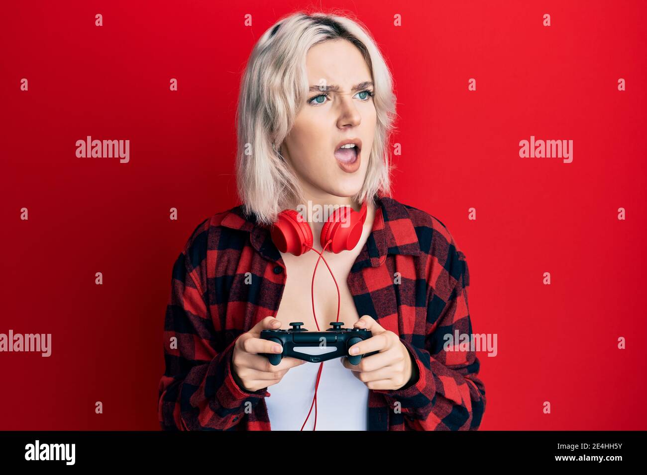 Young blonde girl playing video game holding controller angry and mad ...