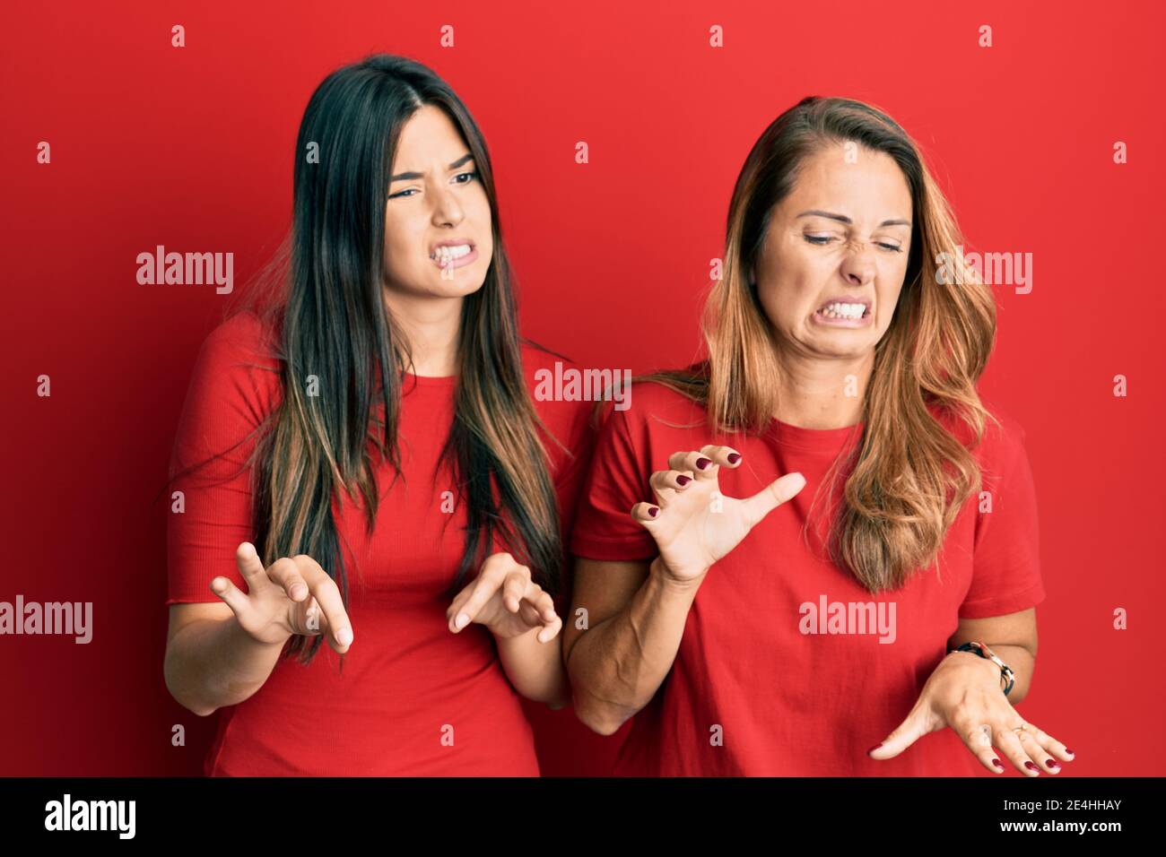 Hispanic family of mother and daughter wearing casual clothes over red ...