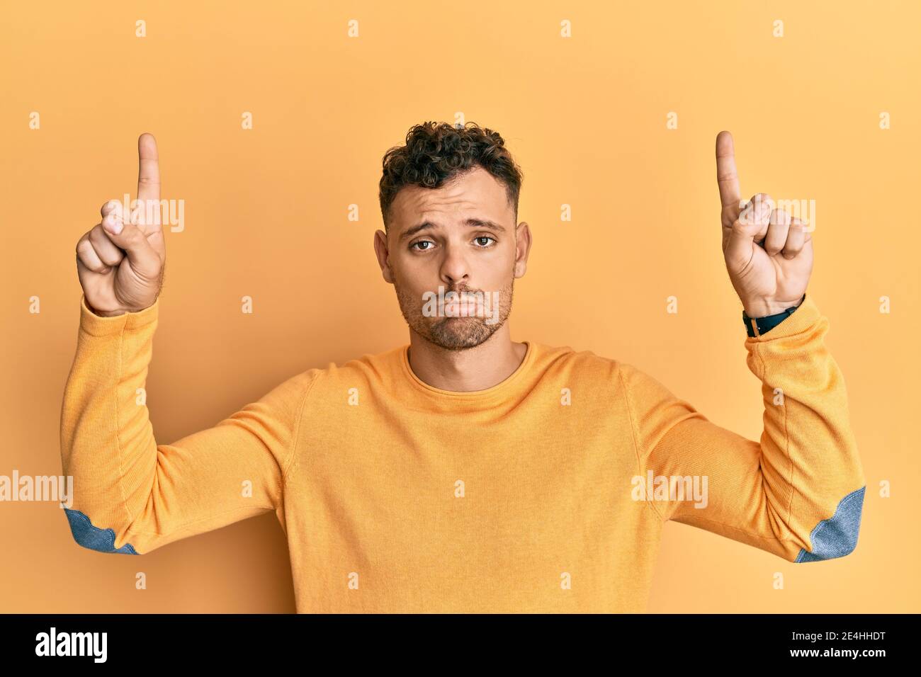 Young hispanic man pointing up with fingers depressed and worry for ...