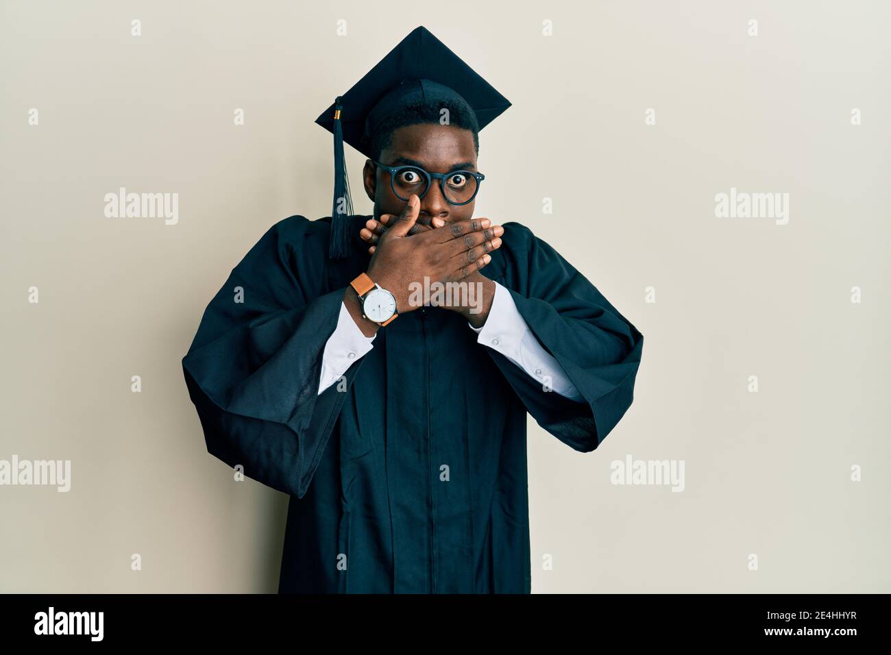 Handsome black man wearing graduation cap and ceremony robe shocked ...