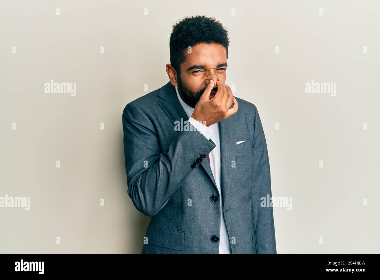 Handsome hispanic man with beard wearing business suit and tie smelling ...