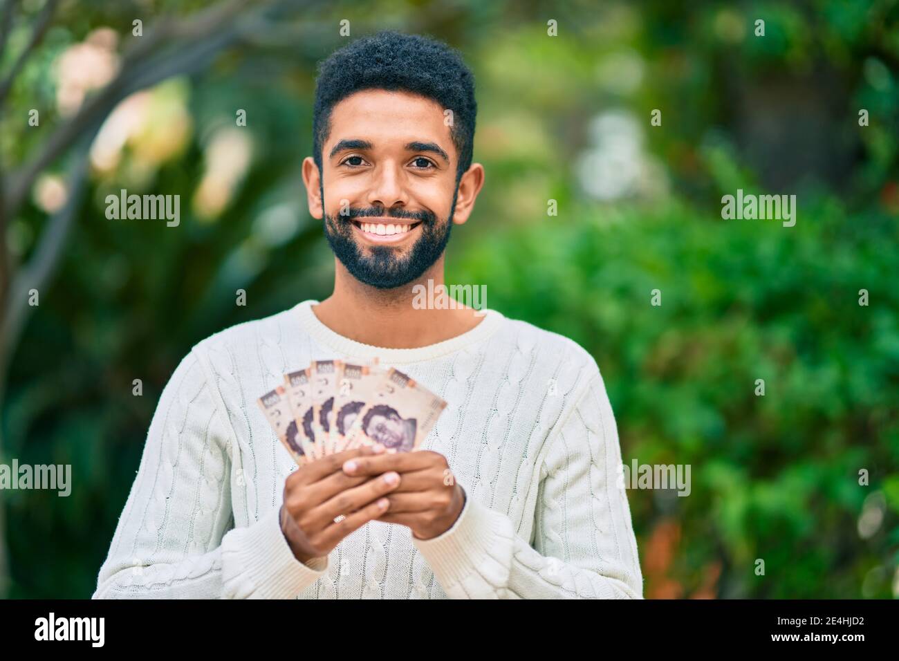 Young african american man smiling happy holding mexican 500 pesos ...