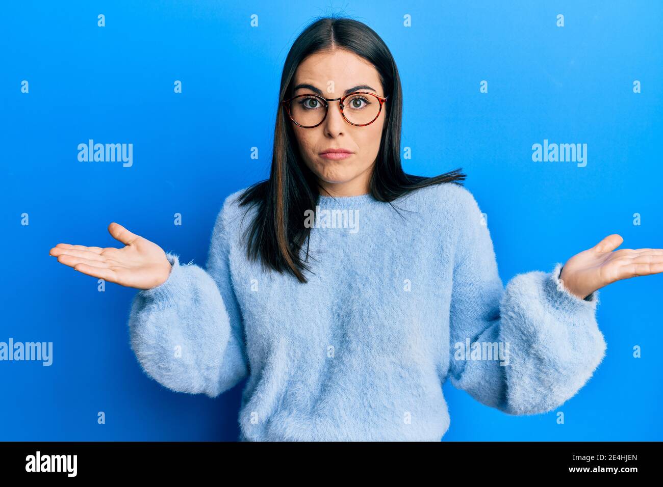 Young brunette woman wearing casual clothes and glasses clueless and ...