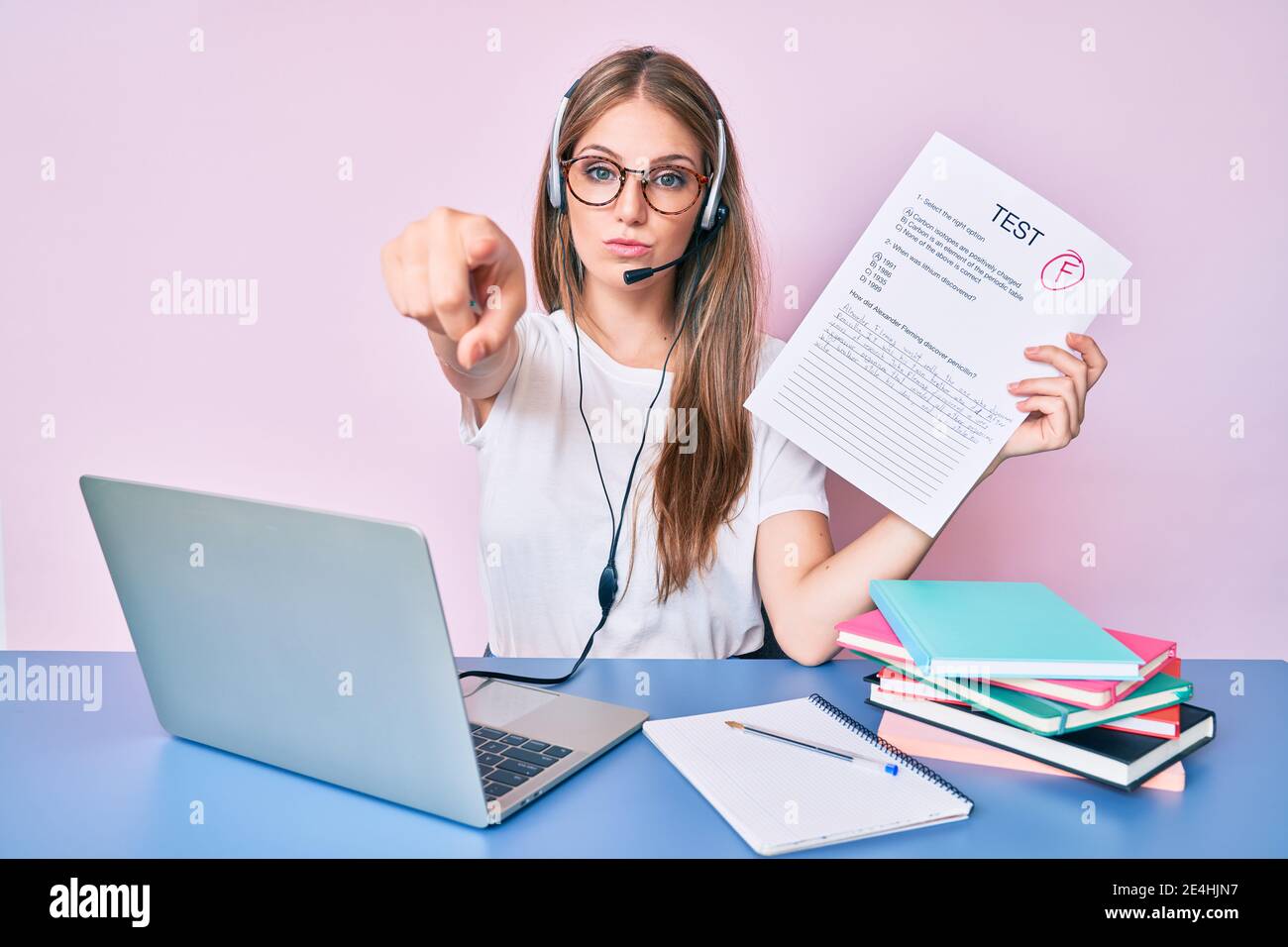Young blonde girl showing failed exam sitting on the table pointing ...