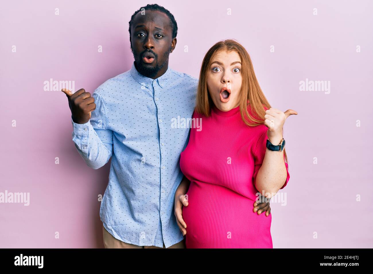 Young interracial couple expecting a baby, touching pregnant belly ...