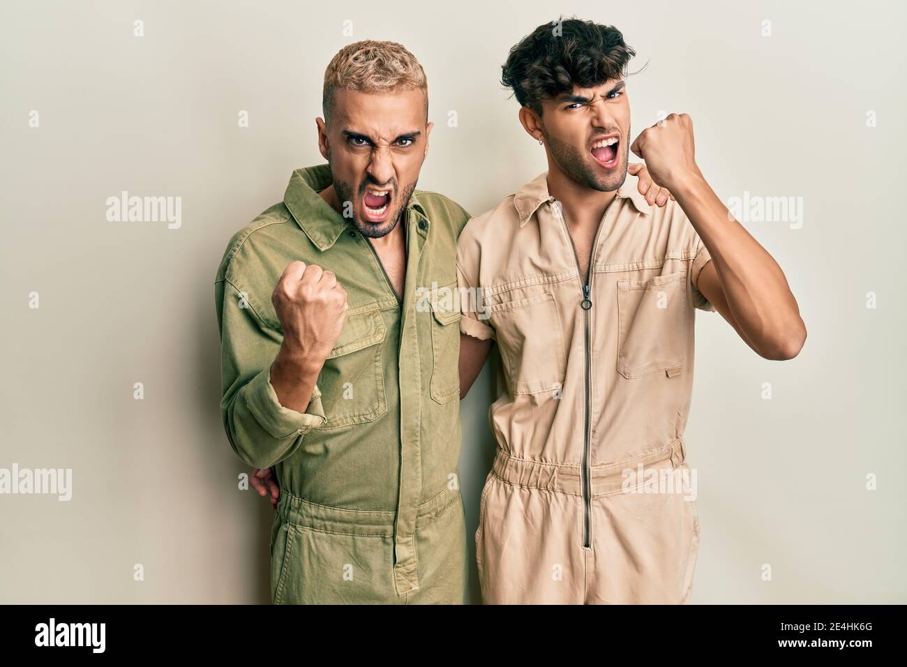 Homosexual gay couple standing together wearing casual jumpsuit angry ...