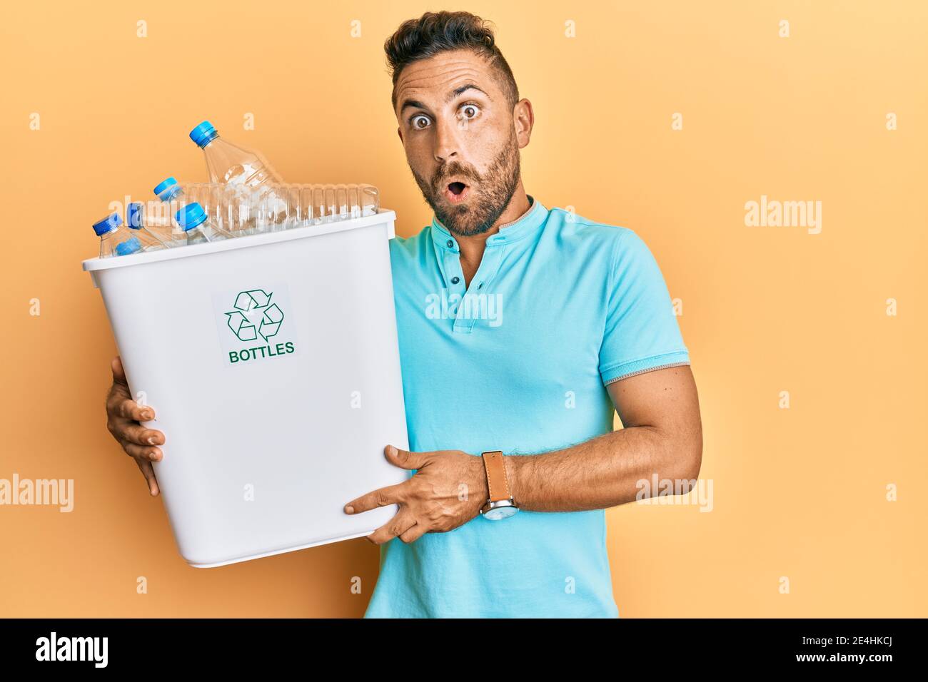Handsome man with beard holding recycling wastebasket with plastic ...