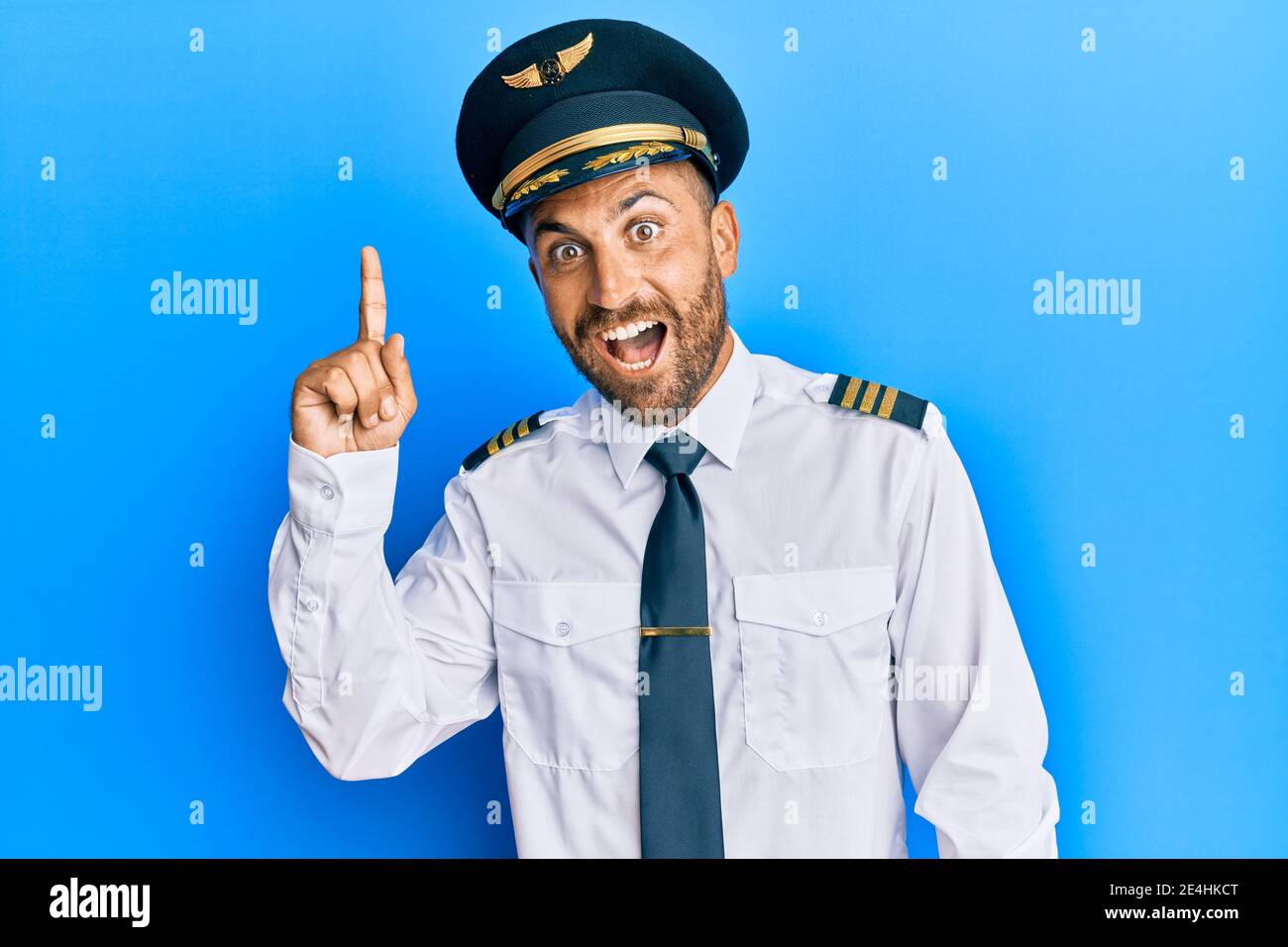 Handsome man with beard wearing airplane pilot uniform pointing finger ...