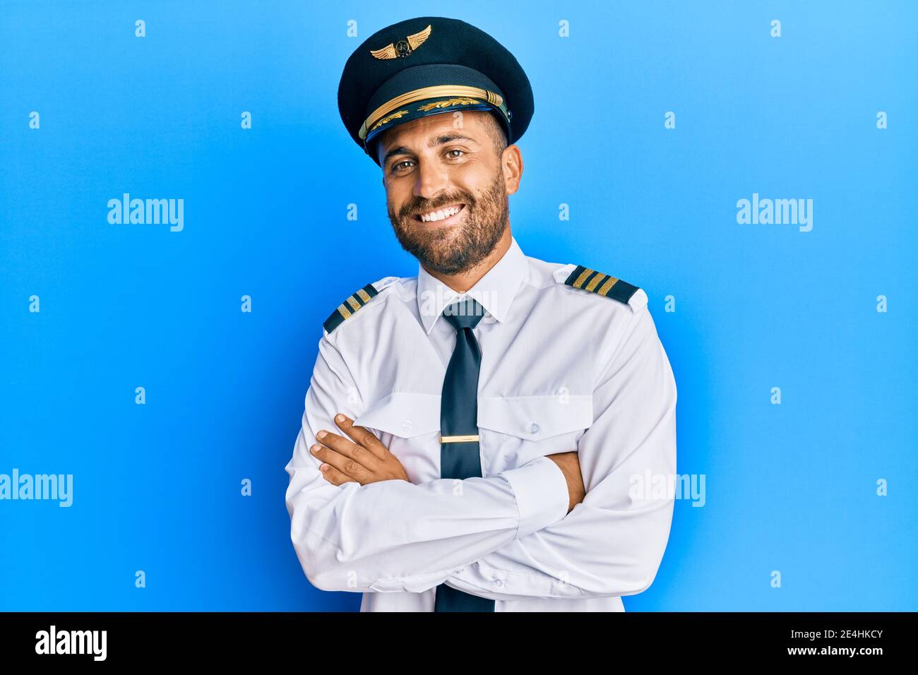 Handsome man with beard wearing airplane pilot uniform happy face ...