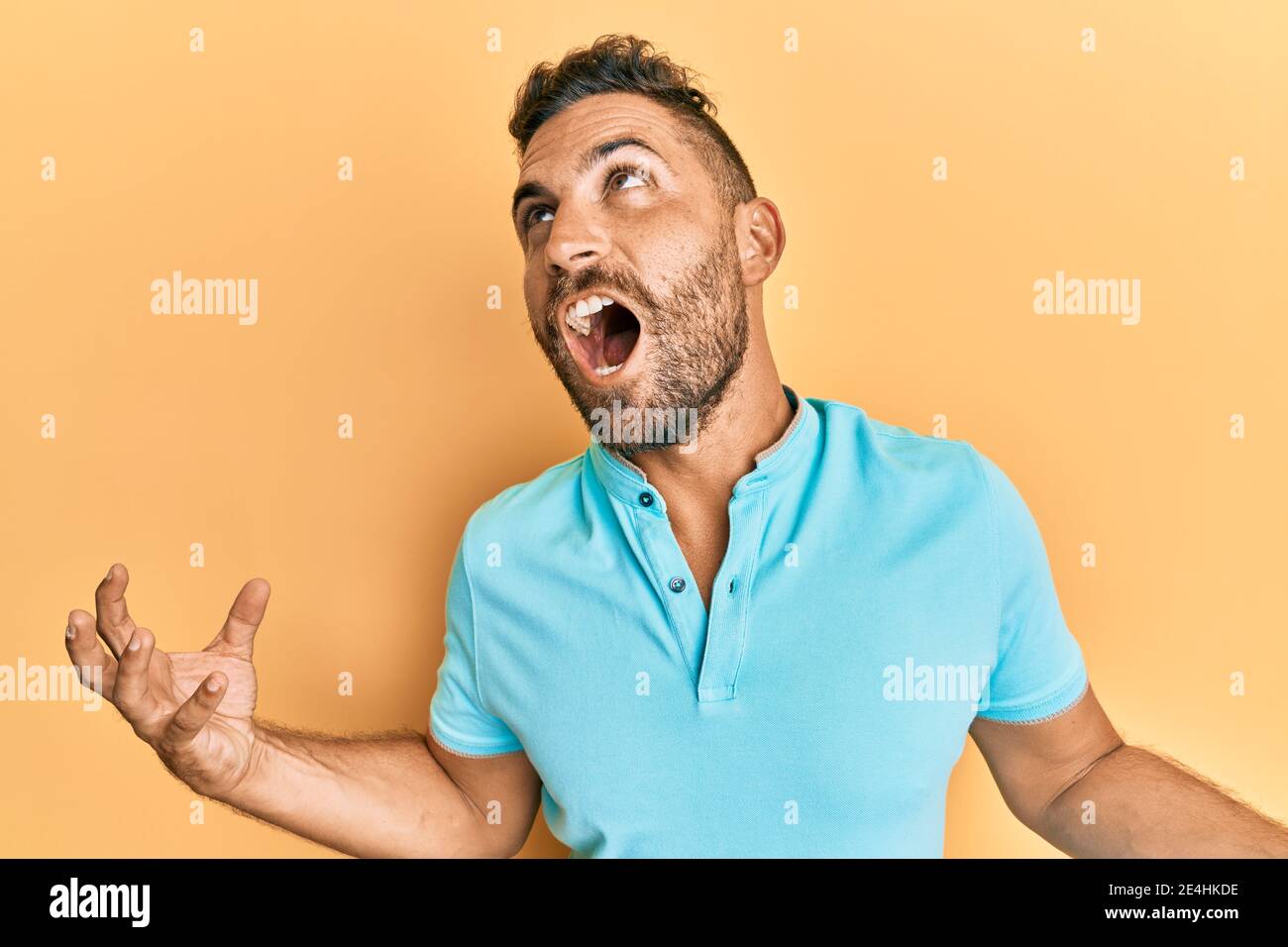 Handsome man with beard wearing casual clothes crazy and mad shouting ...