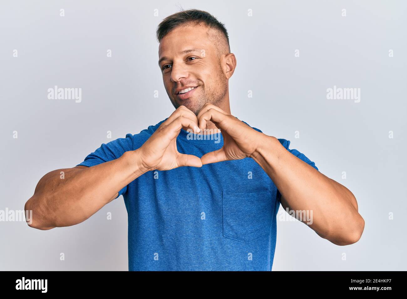 Handsome muscle man wearing casual clothes smiling in love doing heart ...