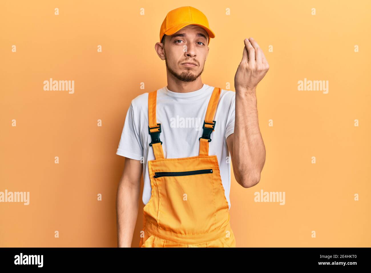 Hispanic young man wearing handyman uniform doing italian gesture with ...