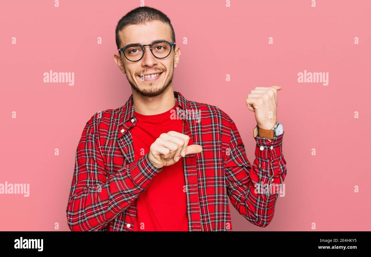 Hispanic young man wearing casual clothes pointing to the back behind ...