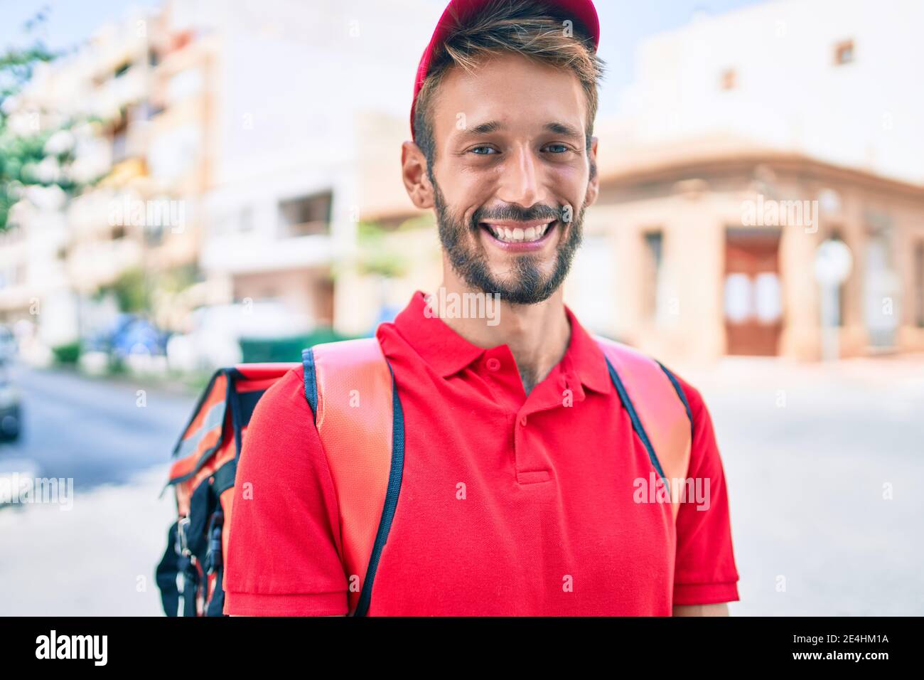 Caucasian delivery man wearing red uniform and delivery backpack smilly ...