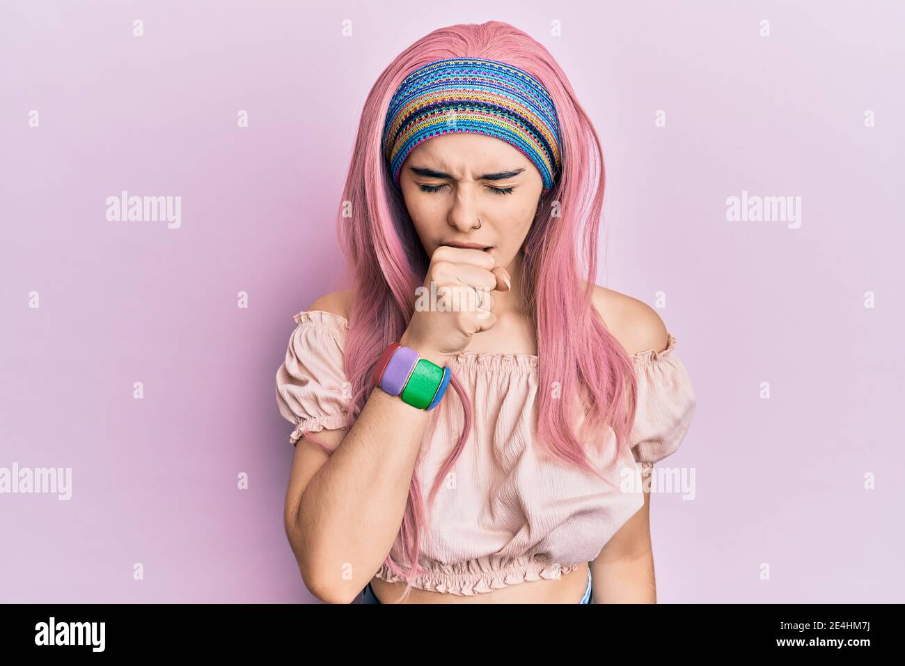 Young hispanic girl with pink hair feeling unwell and coughing as ...