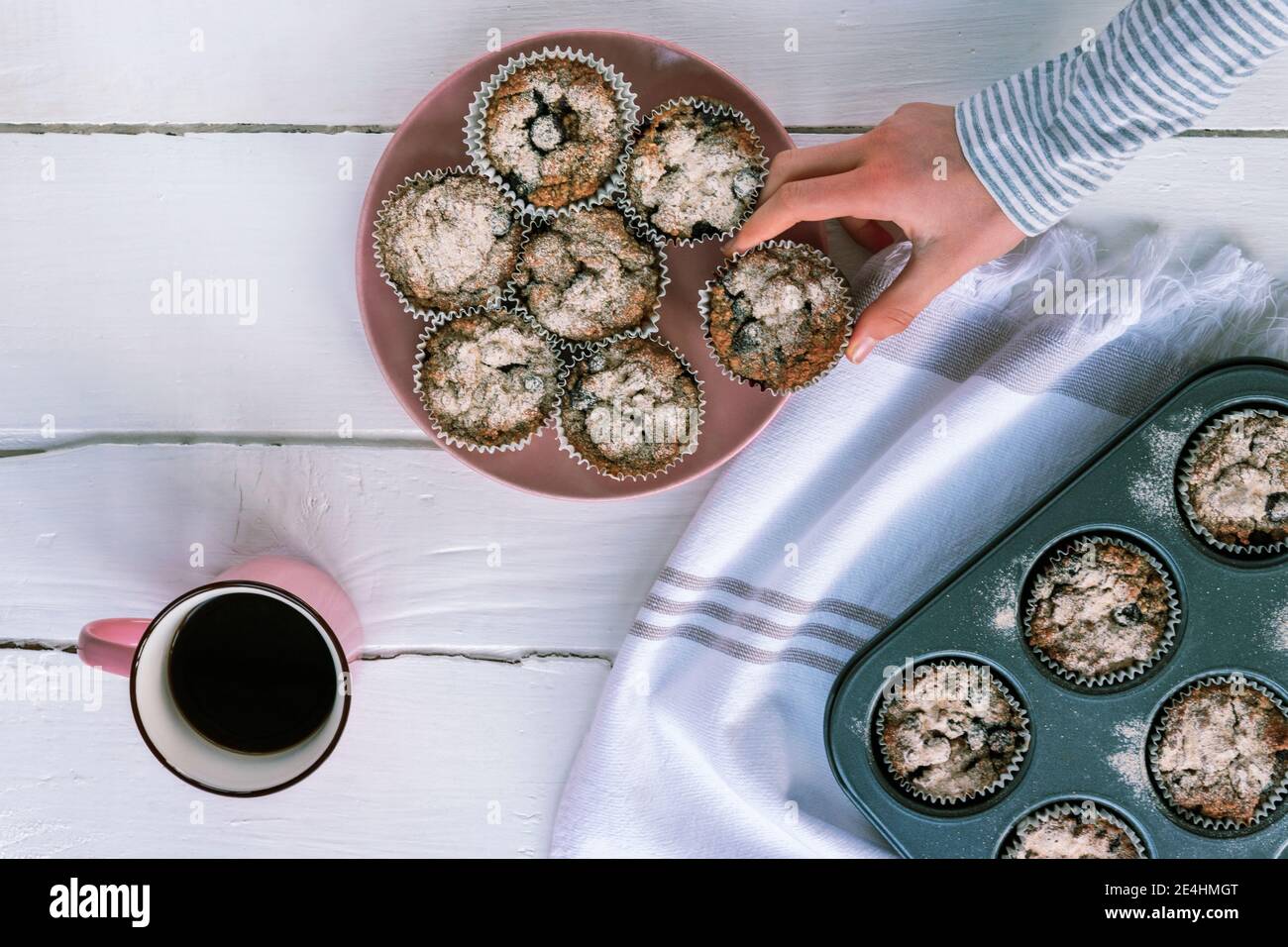 The girl's hand takes the muffin from the plate, top view, flat lay ...