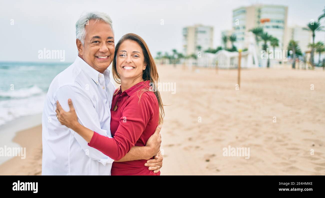 Middle age hispanic couple smiling happy and hugging walking at the ...