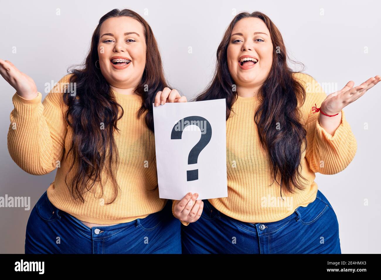 Young plus size twins holding question mark celebrating victory with ...